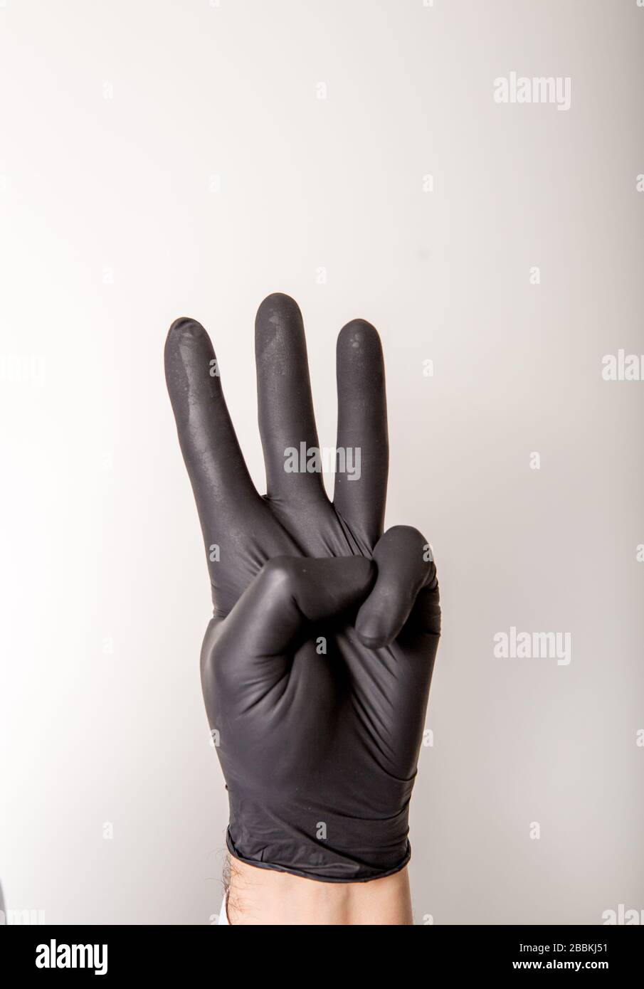 Sign made of black medical gloves. Fingers symbol three. Isolated on ...