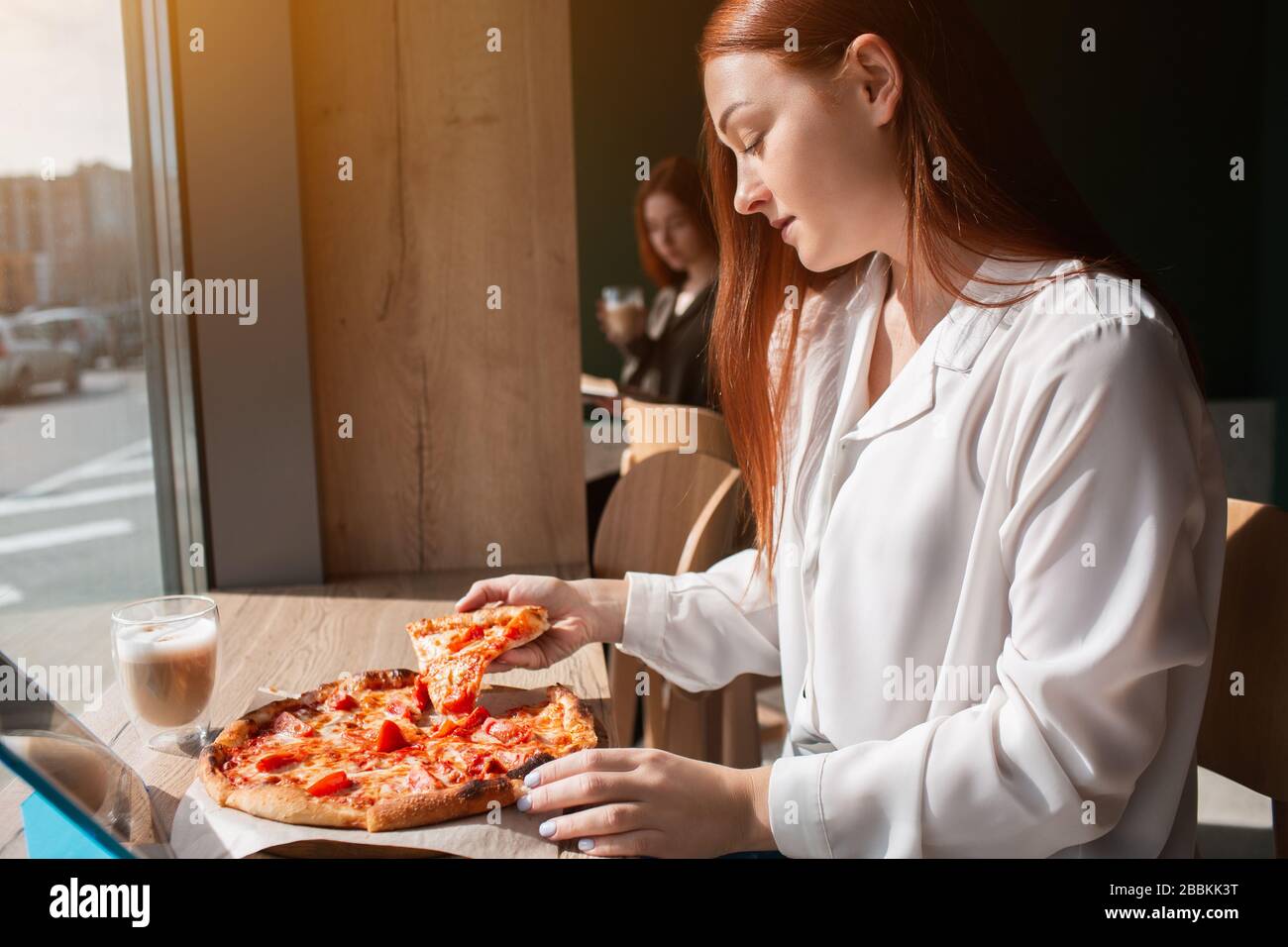 Female model holds a piece of pizza in her hands. Young woman eating ...