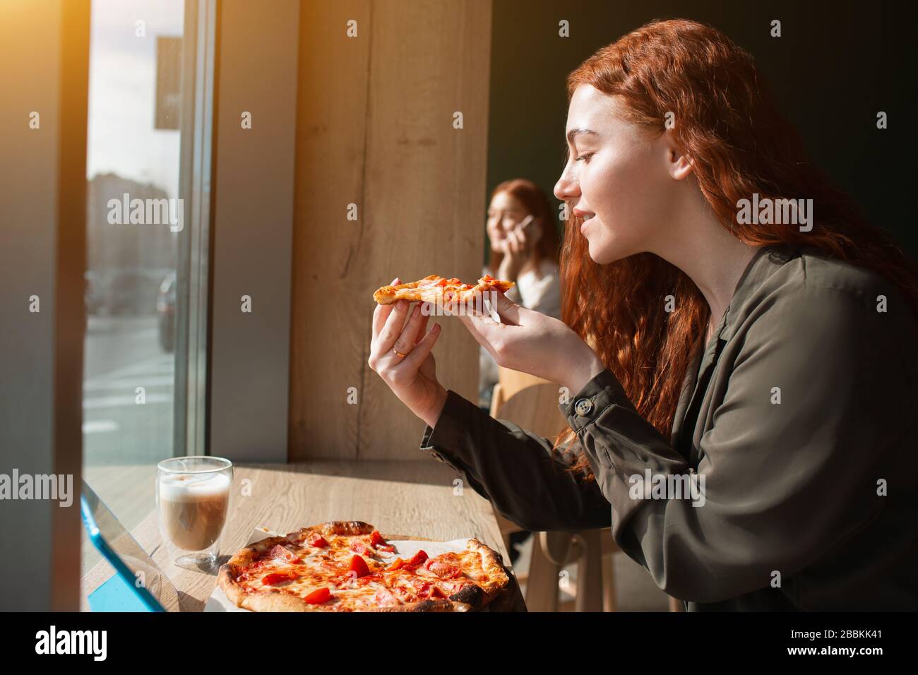 Female model holds a piece of pizza in her hands. Young woman eating ...