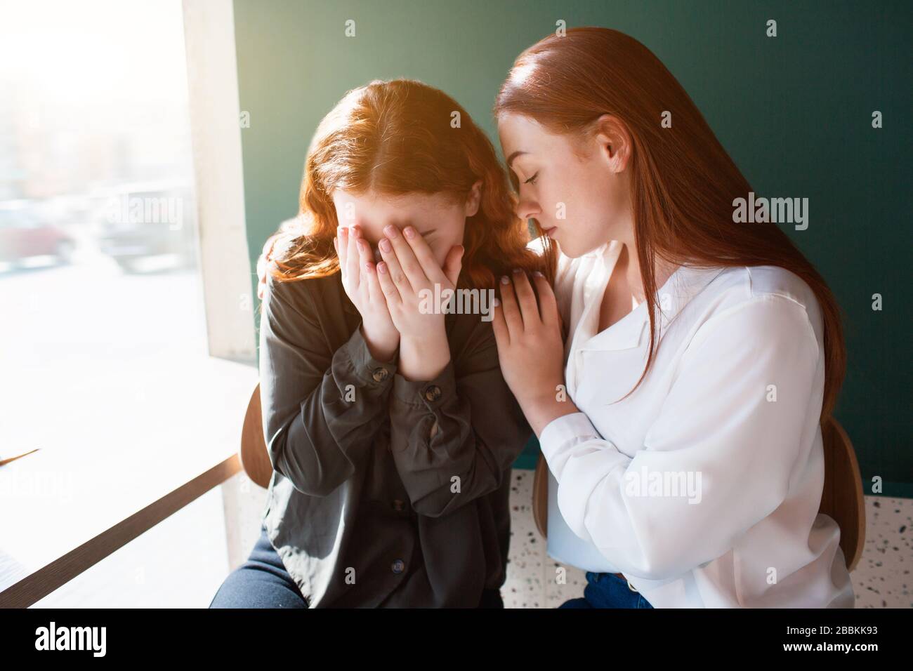 Young woman crying in a cafe covers her face with her hands. Female ...