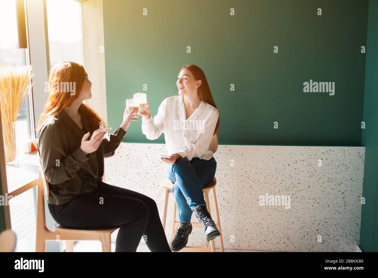 Female models drink coffee in a cafe. Young women talk and smile Stock ...
