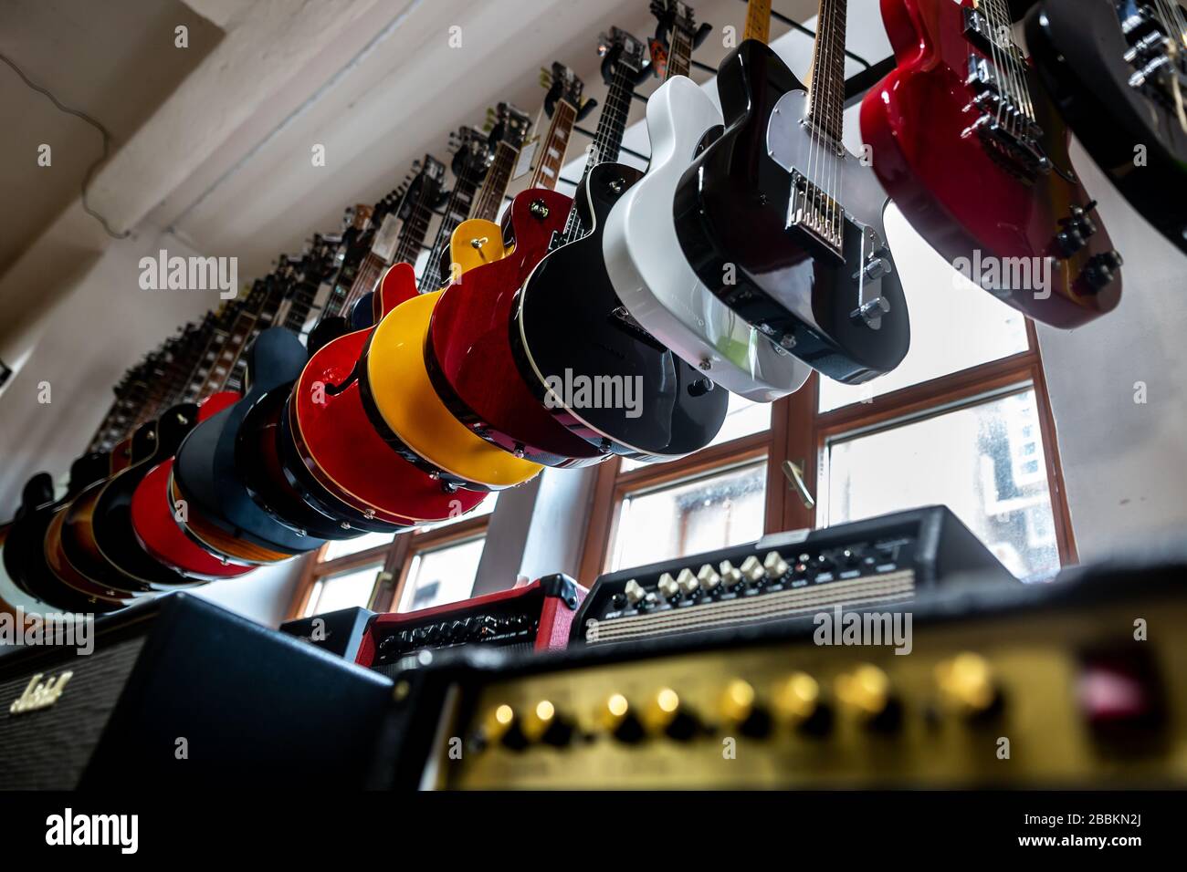 Huge arrenge of professional electric guitars draped in a row in a shop ...
