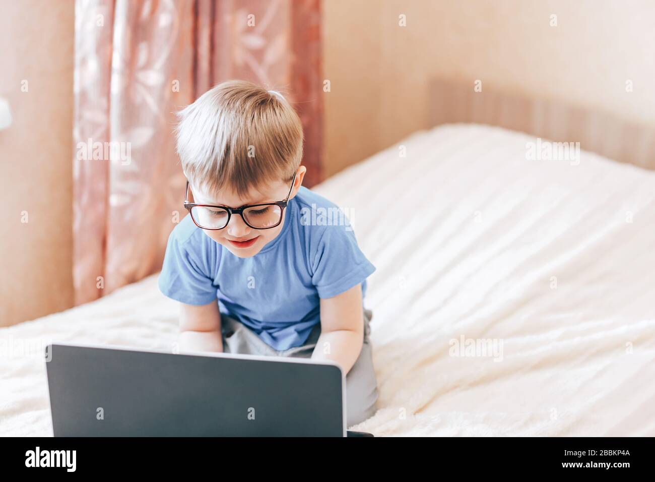Little happy blonde boy using laptop Stock Photo - Alamy