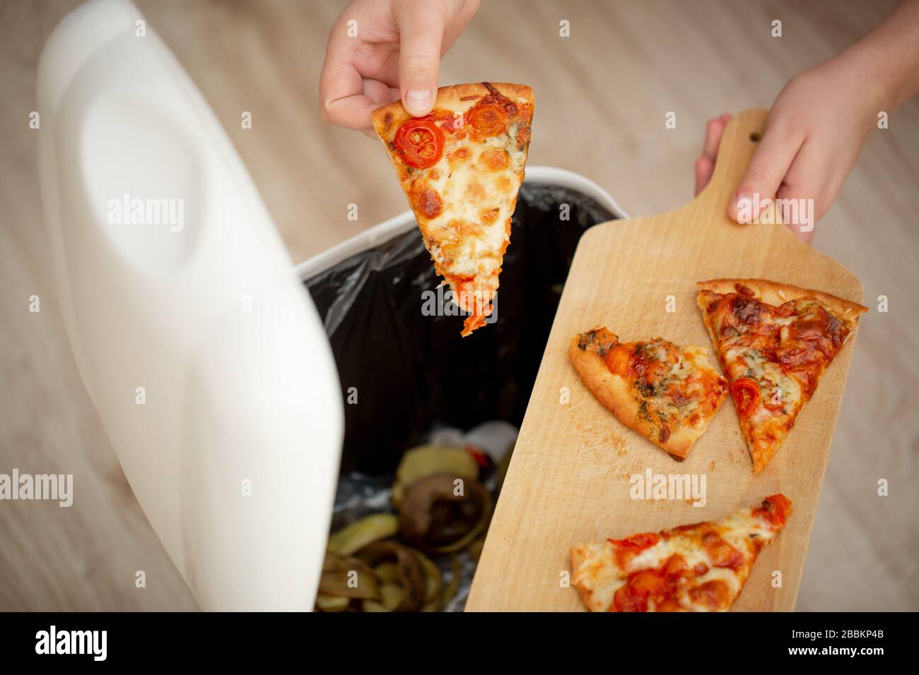 Stop food waste, young woman throwing leftover food into a trash can ...