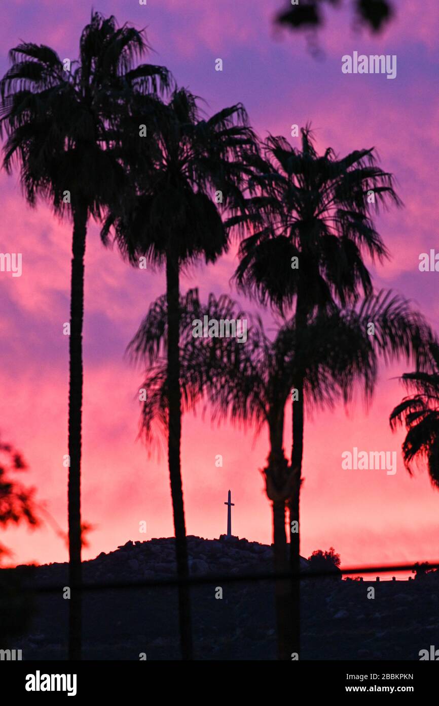 General overall view of sunset at dusk of the cross and palm trees atop ...