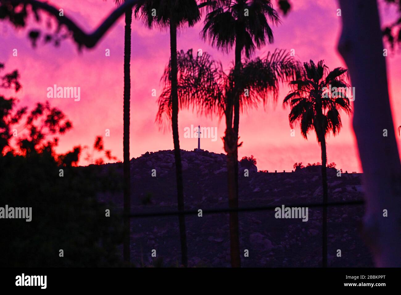 General overall view of sunset at dusk of the cross and palm trees atop ...