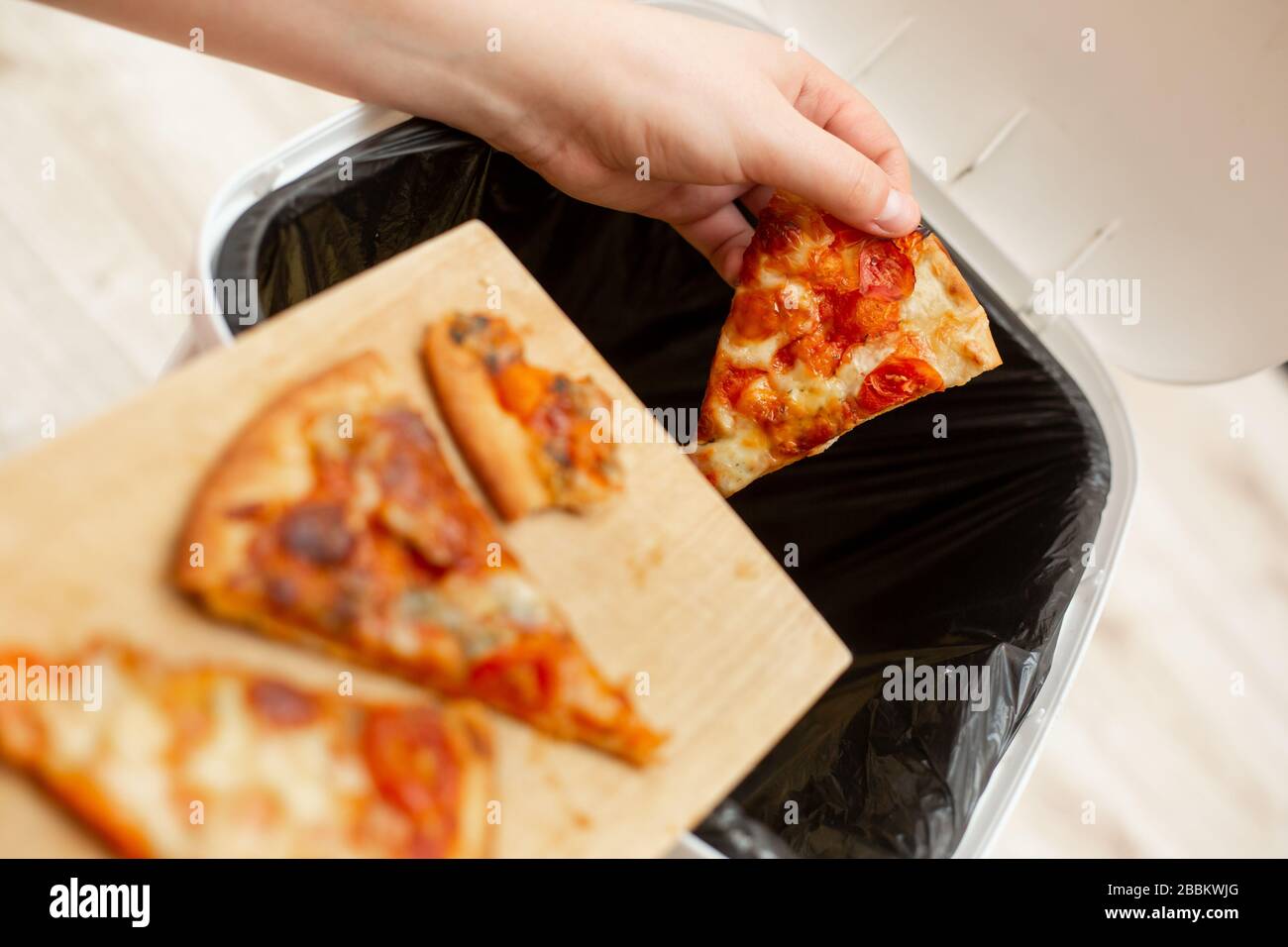 Stop food waste, young woman throwing leftover food into a trash can ...