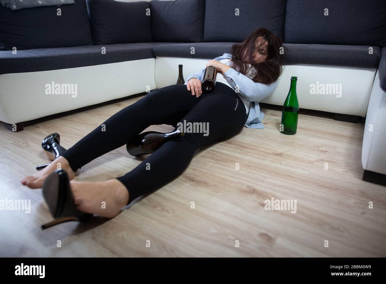 Drunk woman lying on the sofa with kind of wine bottles, alcoholism ...