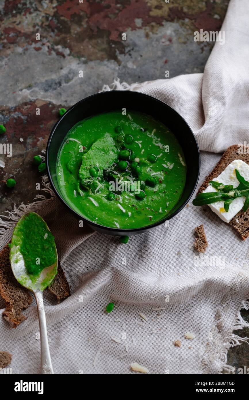Green peas and spinach puree soup in a black bowl. Vegetarian cream ...