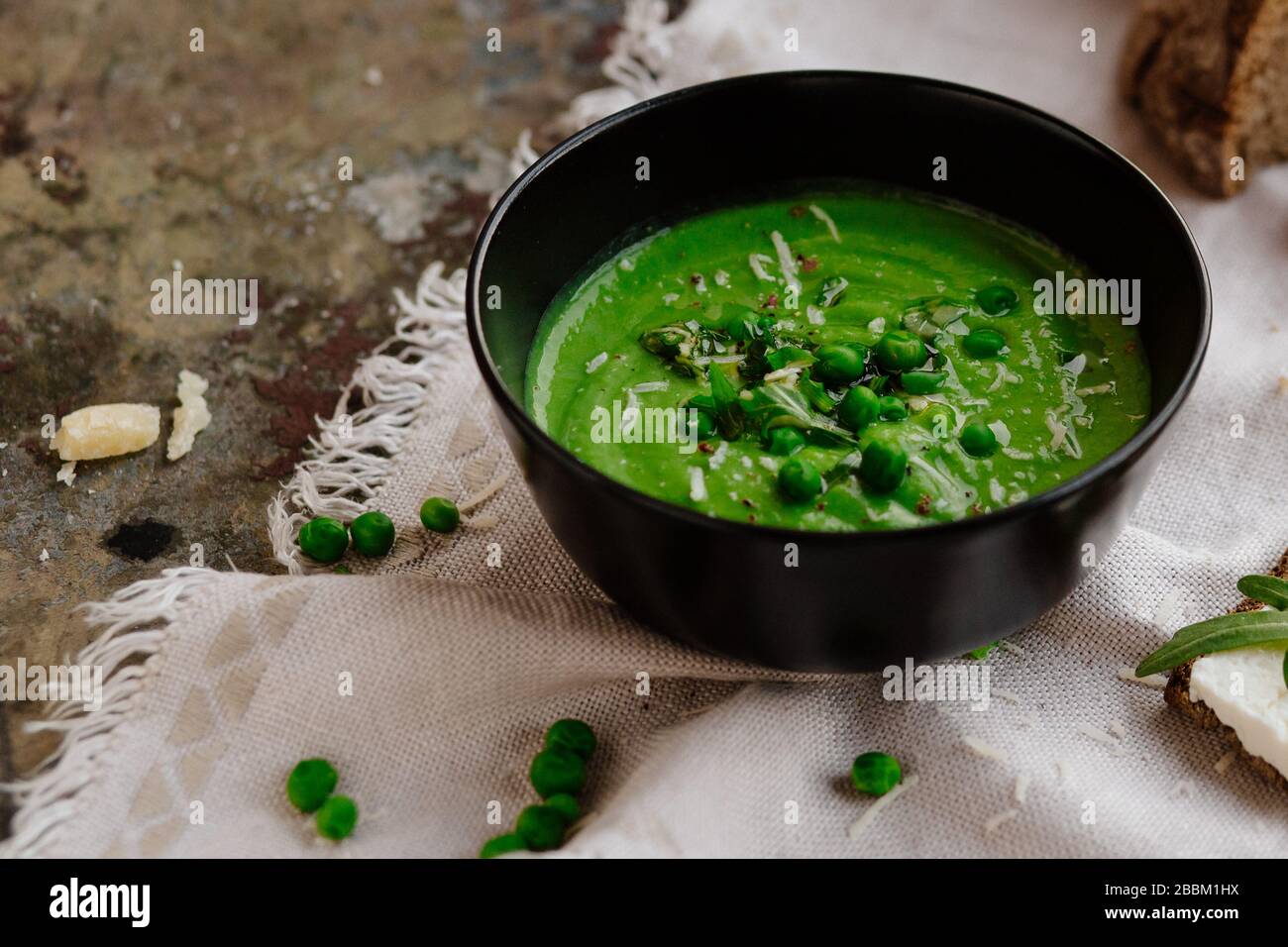 Green peas and spinach puree soup in a black bowl. Vegetarian cream ...