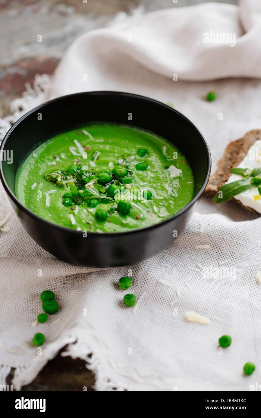 Green peas and spinach puree soup in a black bowl. Vegetarian cream ...