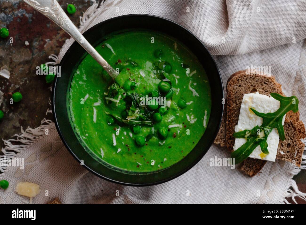 Green peas and spinach puree soup in a black bowl. Vegetarian cream ...