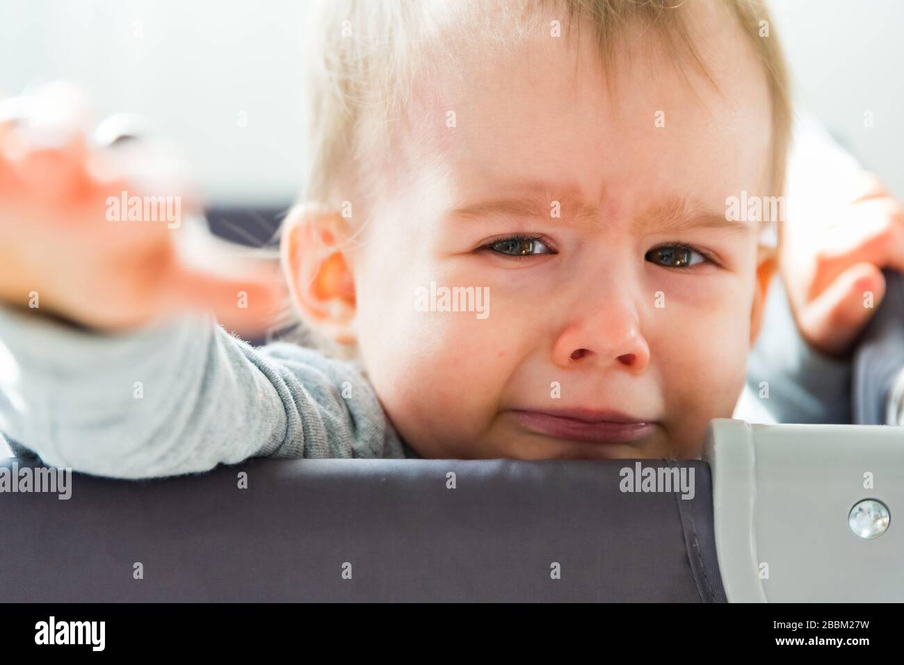 Portrait of one year old baby girl crying and reaching hand towards ...