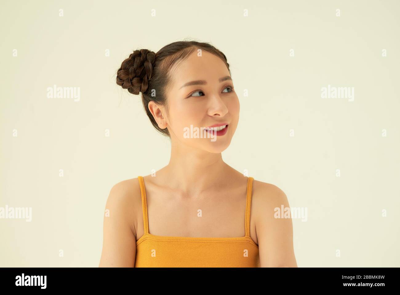 Portrait of young cute Asian girl with two buns against light ...