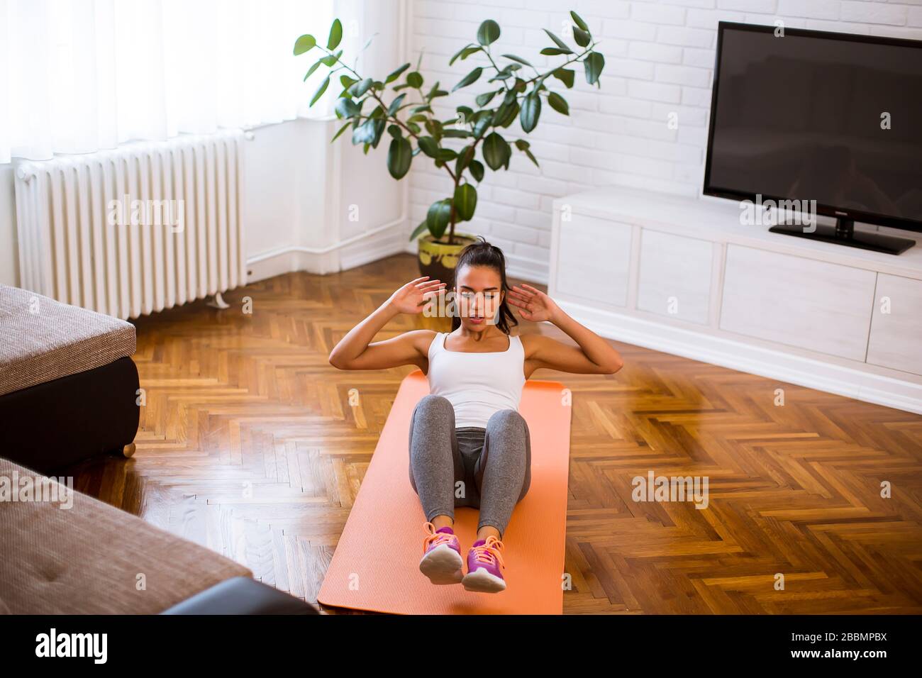 Attractive young female doing exercise in her living room Stock Photo ...
