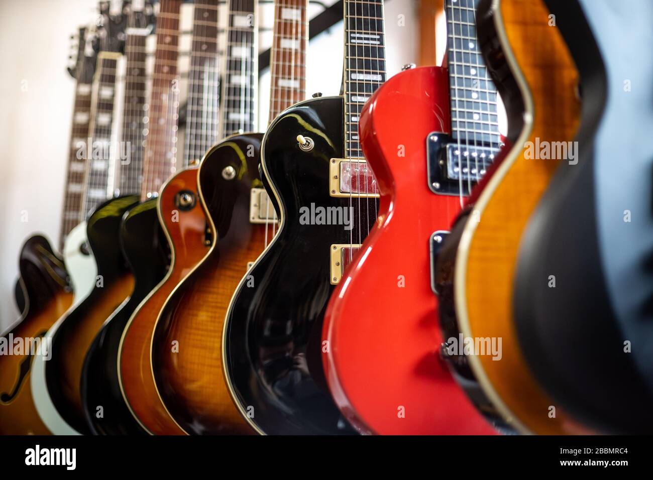 Huge arrenge of professional electric guitars draped in a row in a shop ...