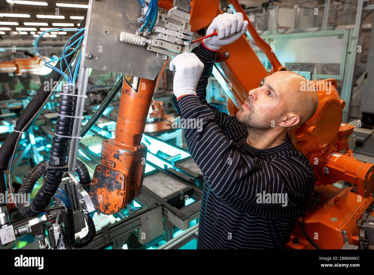 Factory engineer operating with automatic robot arms in automotive ...