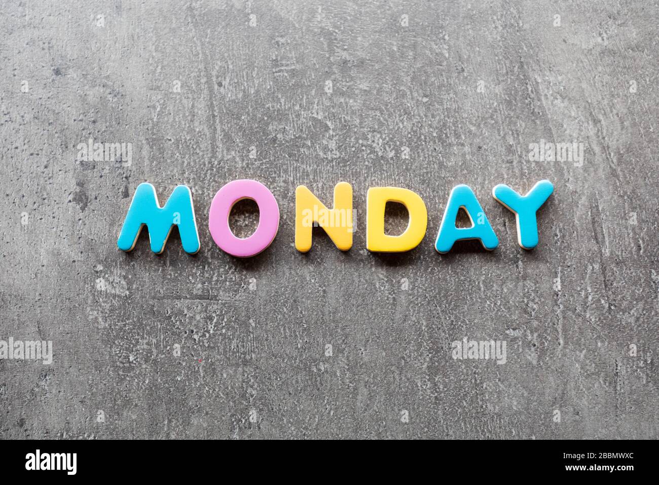 Monday word written with colorful letters on granite stone background ...