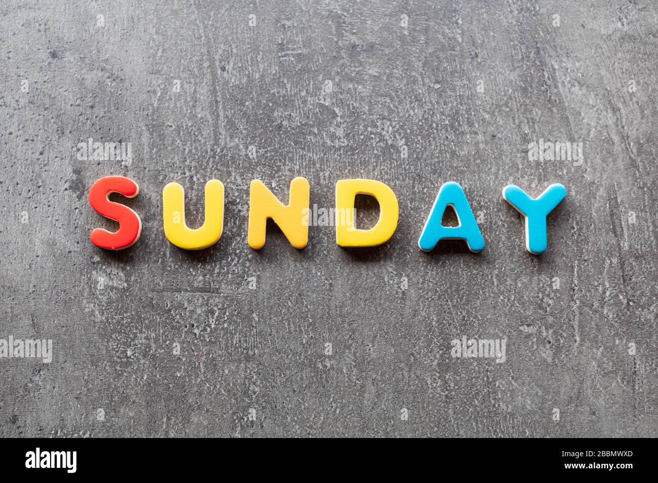 Sunday word written with colorful letters on granite stone background ...