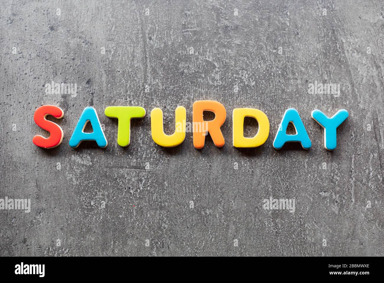 Saturday word written with colorful letters on granite stone background ...