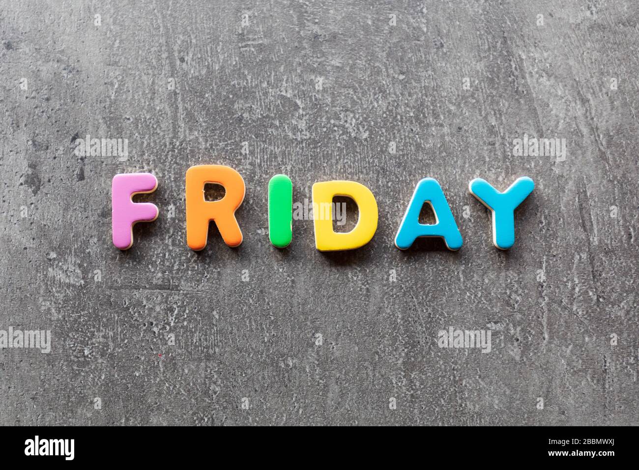 Friday word written with colorful letters on granite stone background ...