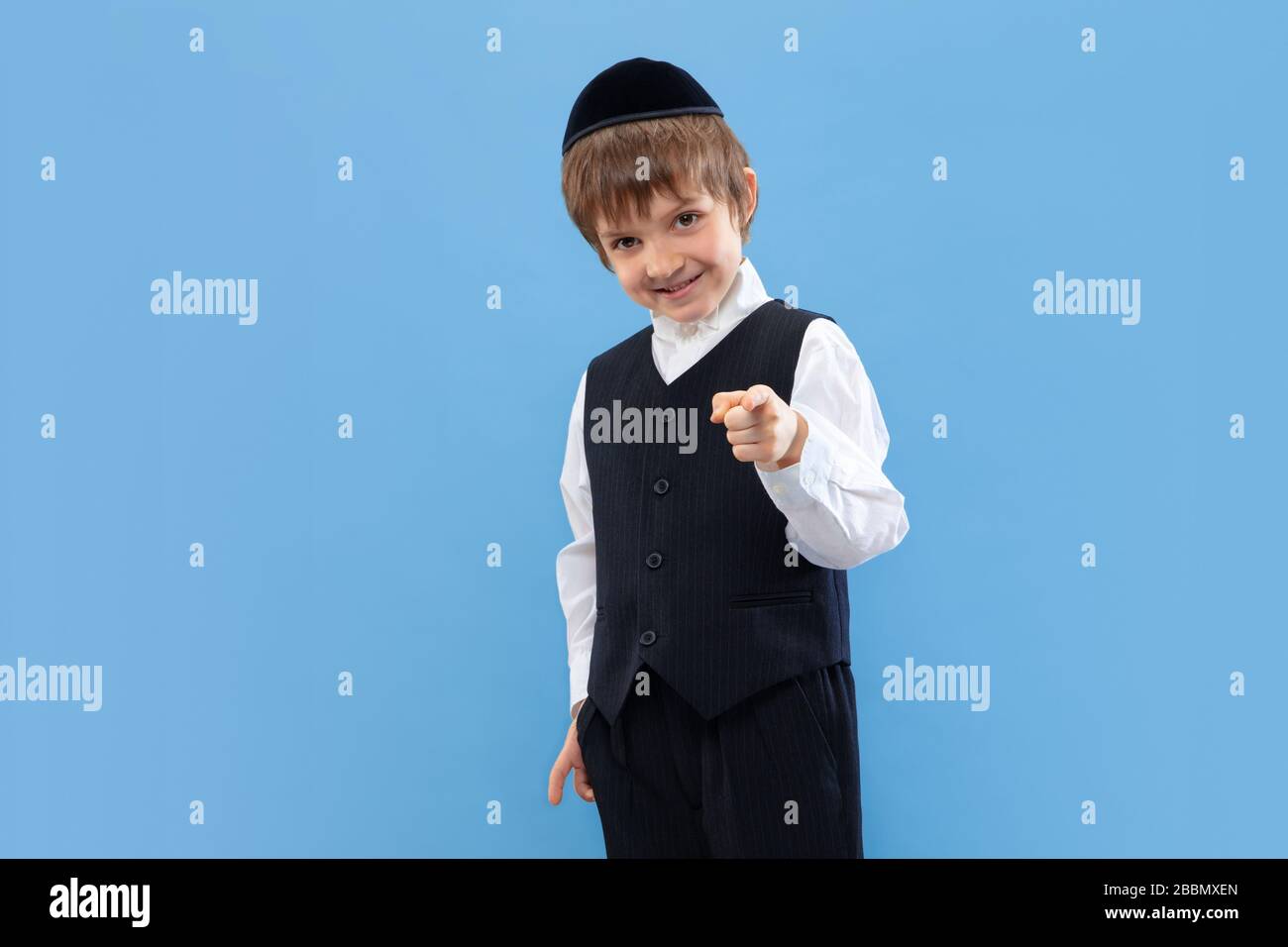 Pointing. Portrait of a young orthodox jewish boy isolated on blue ...