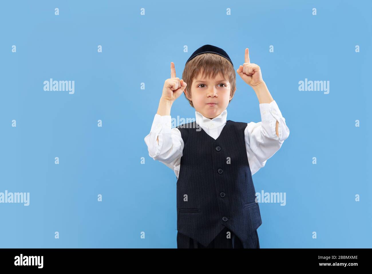 Pointing. Portrait of a young orthodox jewish boy isolated on blue ...