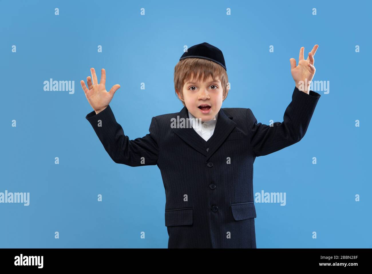 Dancing fun. Portrait of a young orthodox jewish boy isolated on blue ...