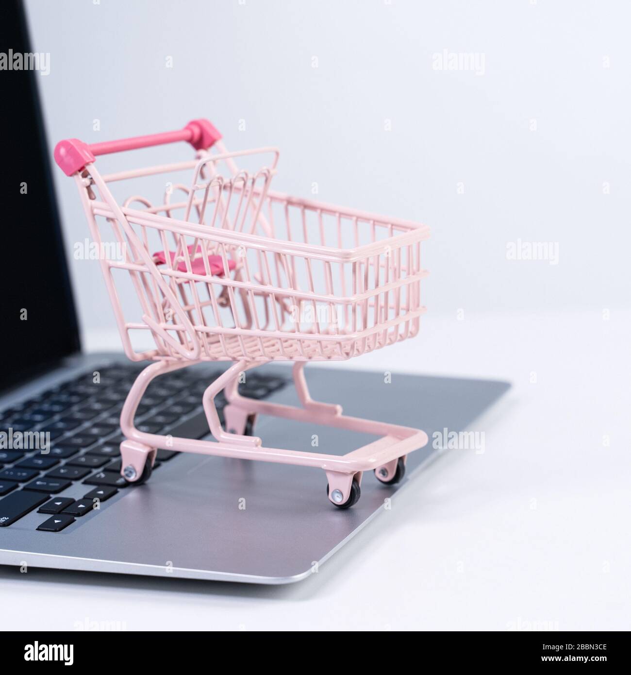 Online shopping. Mini empty pink shop cart trolley over a laptop ...