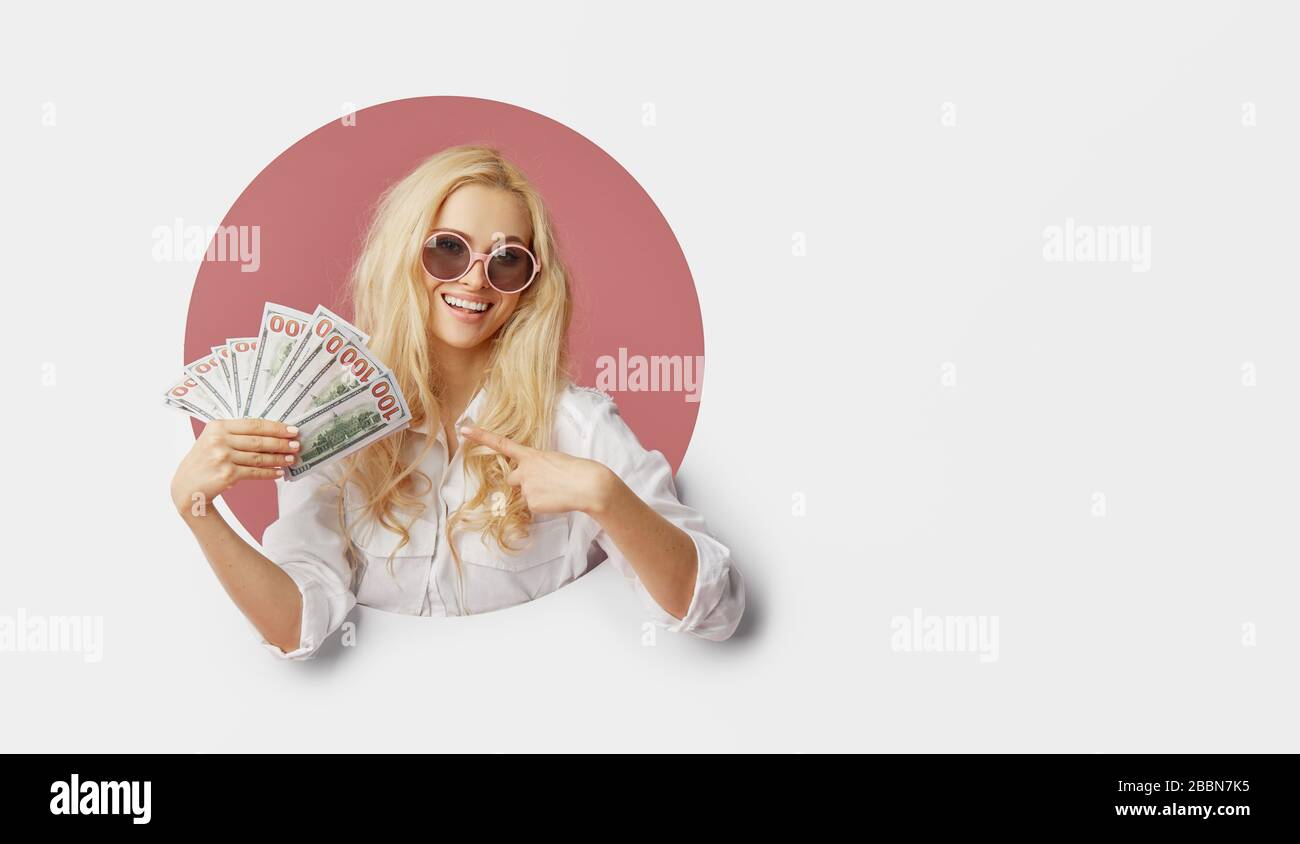 Portrait of a young shocked woman with a bundle of banknotes and text ...