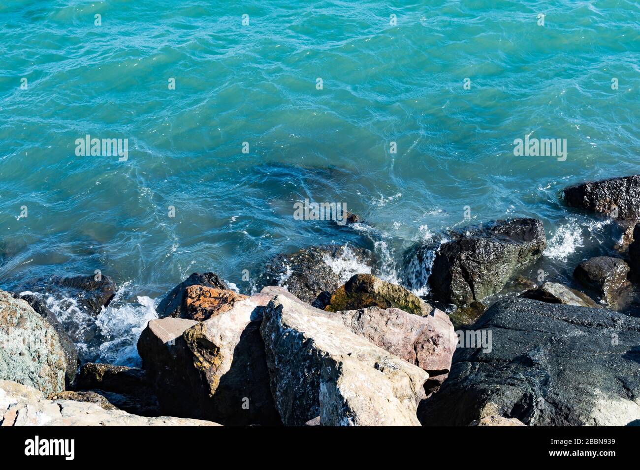 Beach Stones and green ocean water back ground image Stock Photo - Alamy
