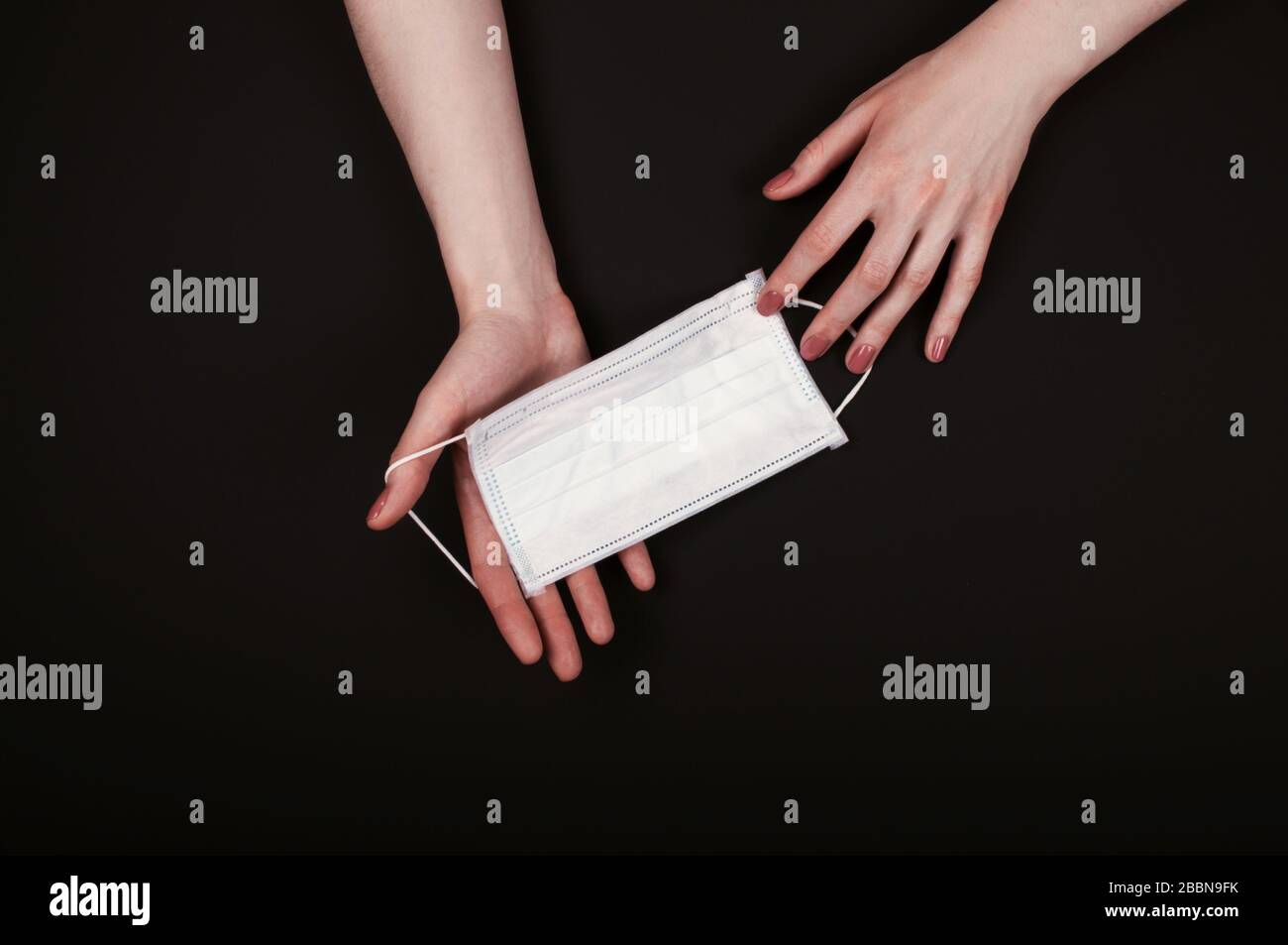 Woman hans hold medicine face mask on black background Stock Photo - Alamy