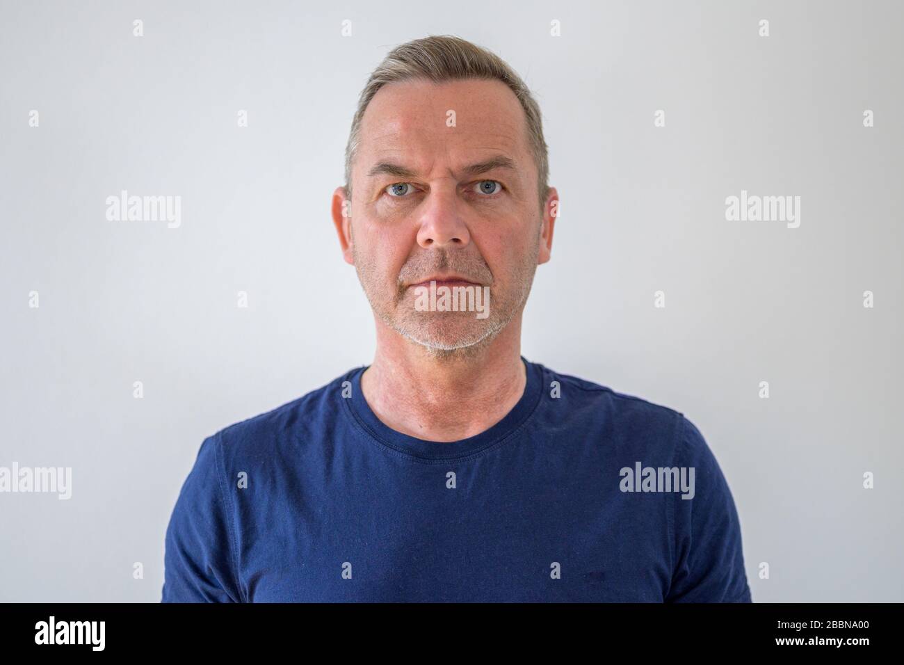 Bust front portrait of middle-aged man in blue t-shirt isolated against ...