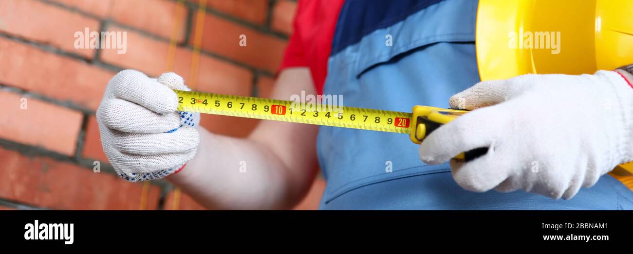 Builder measures dimensions brickwork with tape Stock Photo - Alamy