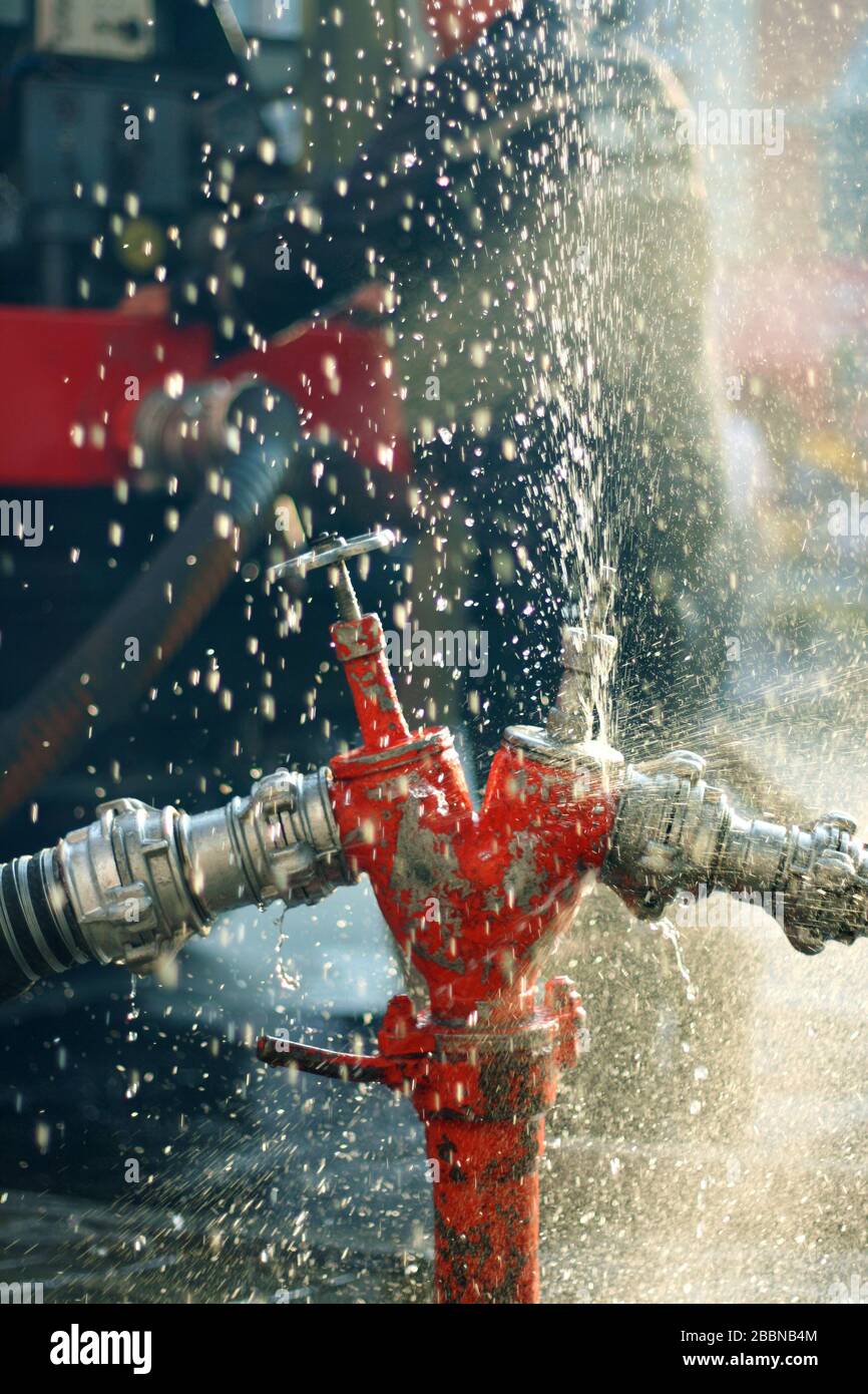 Water splashes from the fire hose and hydrant connections. Firefighters ...