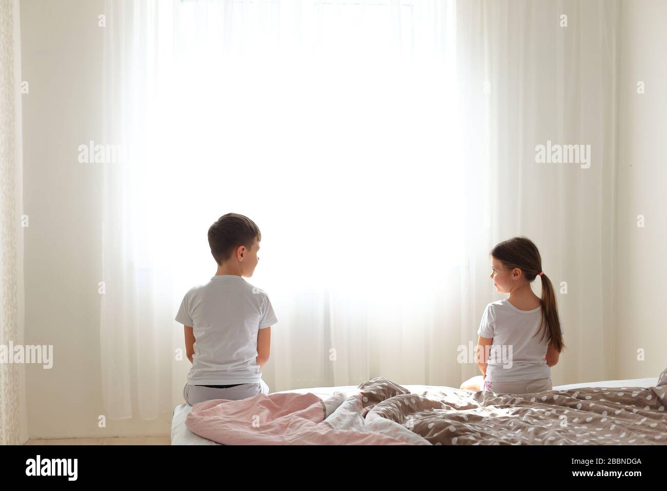 Boy and girl are sitting on the bed at a distance from each other Stock ...