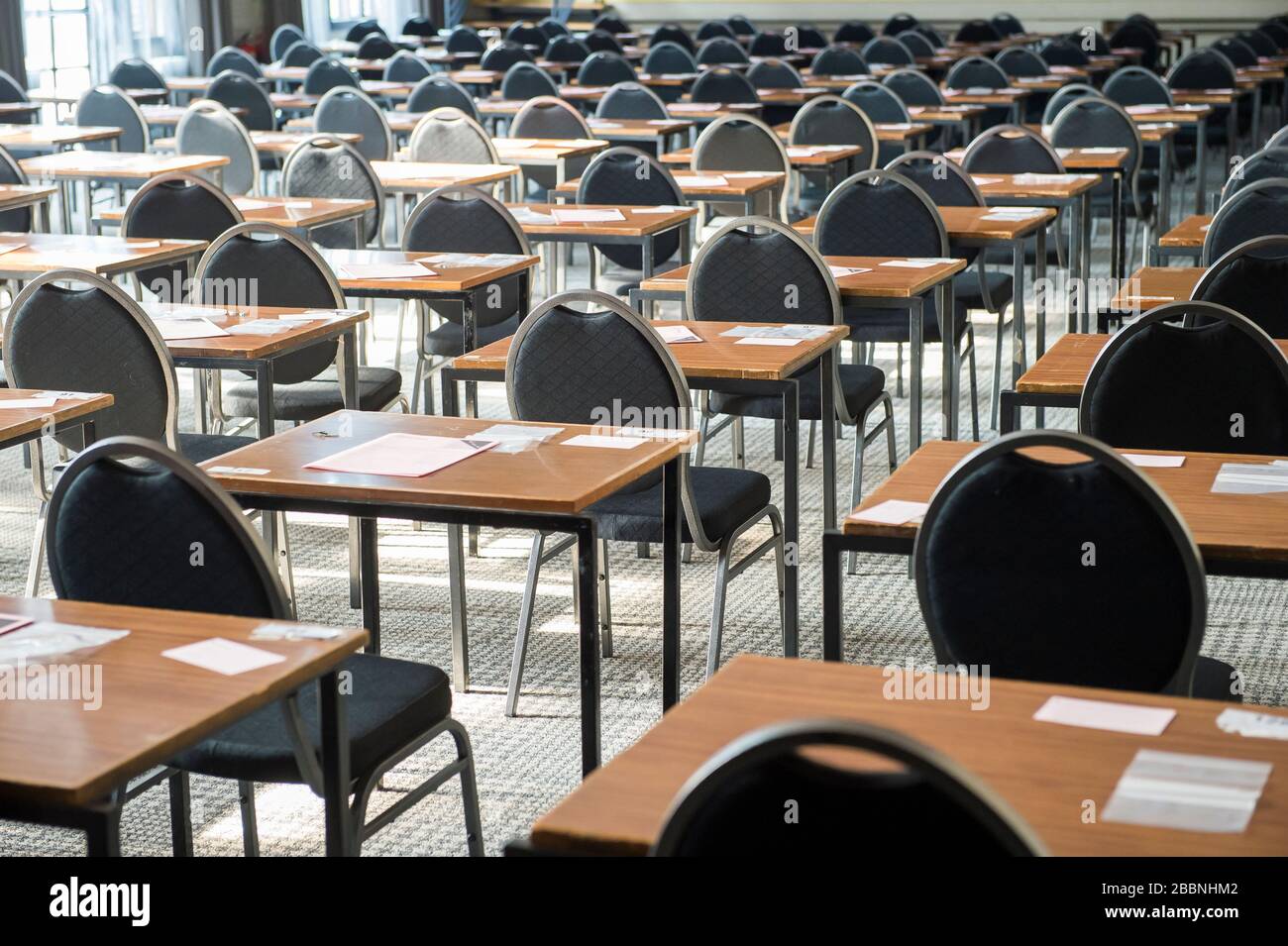 An empty hall of chairs and tables in a school awaiting student exams ...