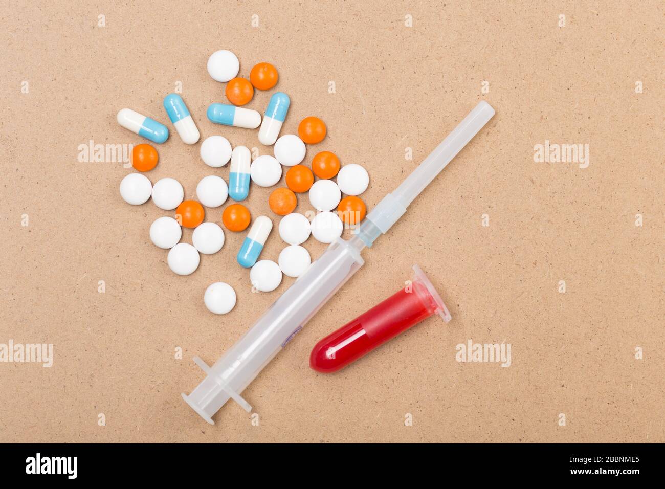 Medicine pills, syringe, blood test tube, tablets and capsules on beige ...