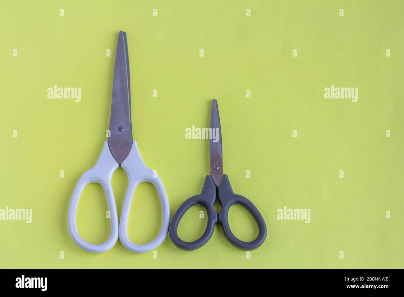 Scissors on a yellow background.White large and black small scissors ...
