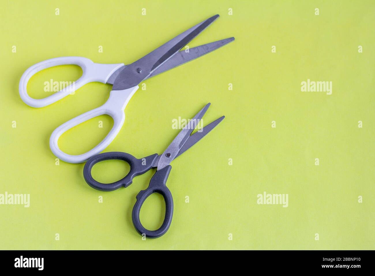 Scissors on a yellow background.White large and black small scissors ...