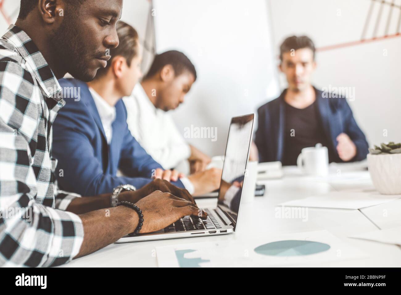 A team of young office workers, businessmen with laptop working at the ...