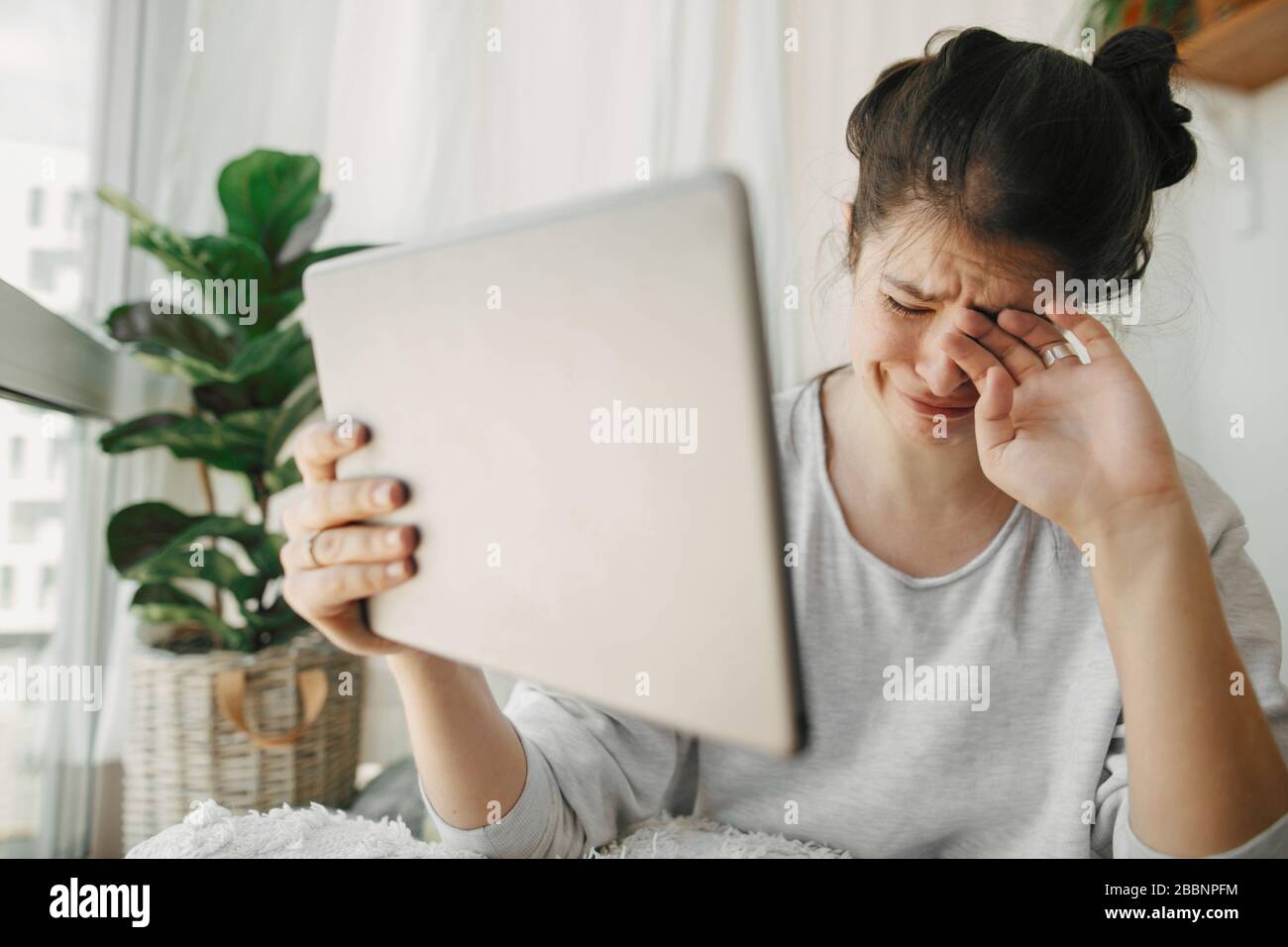 Sad girl crying from bad news from tablet while sitting home in during ...