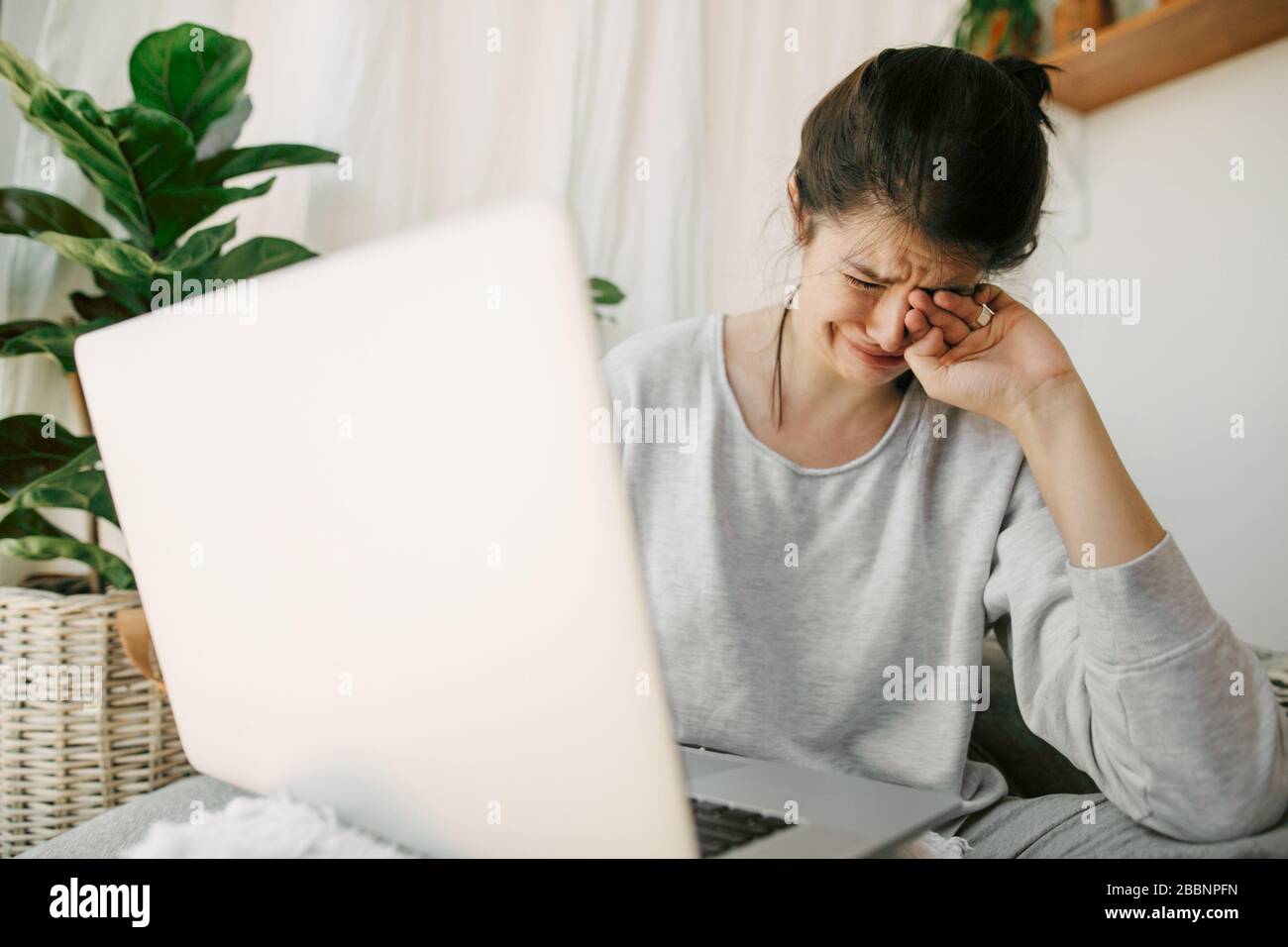 Sad girl crying from bad news, sitting with laptop home alone during ...