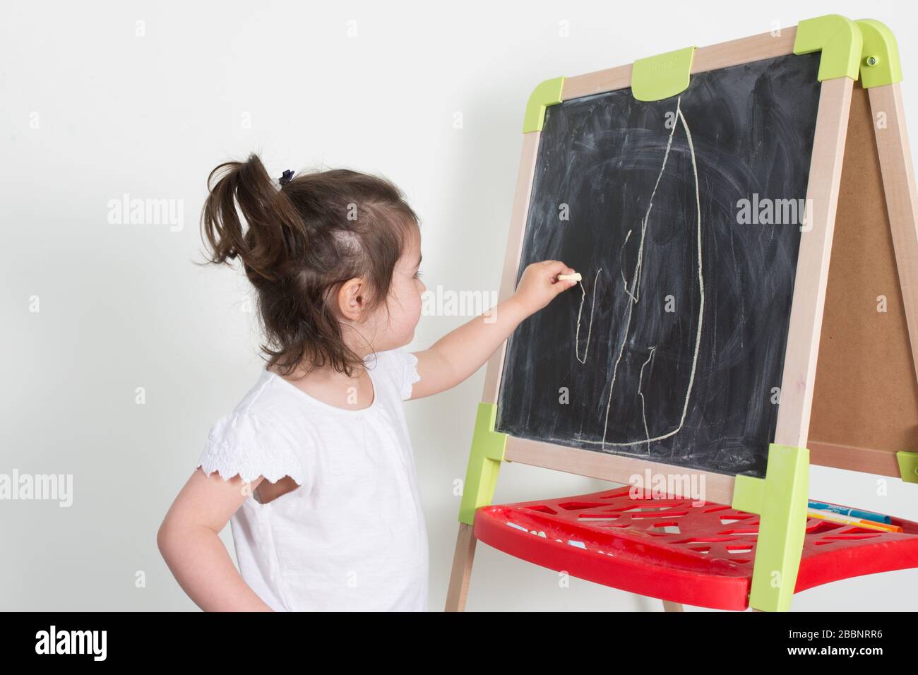 young child girl makes a chalk drawing on the blackboard in toy Stock ...