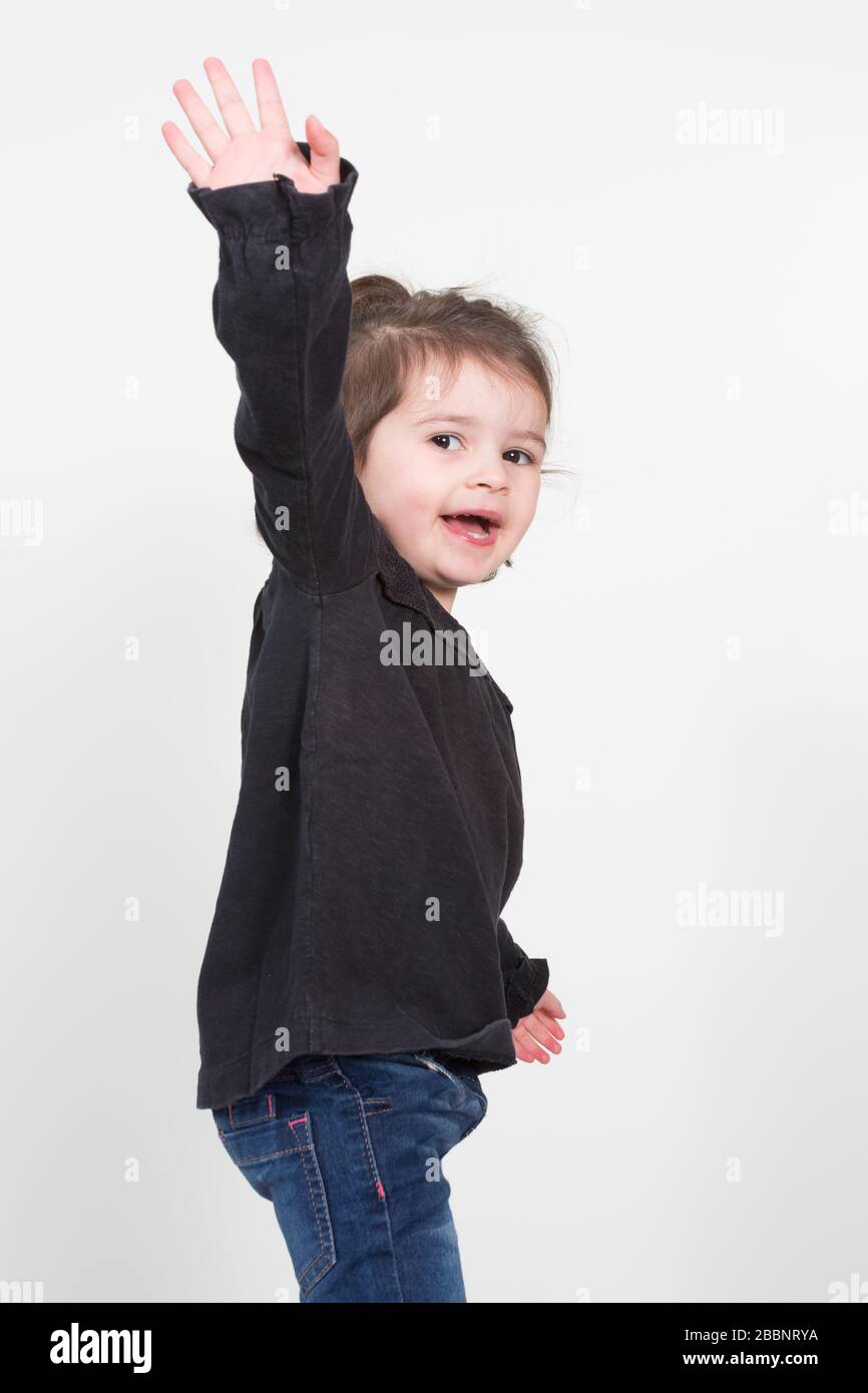 pretty cute young child girl makes goodbye with the hand on a white ...