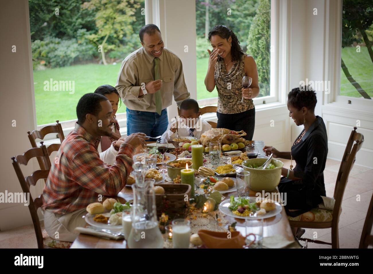 Smiling family gathered around a dining table Stock Photo - Alamy