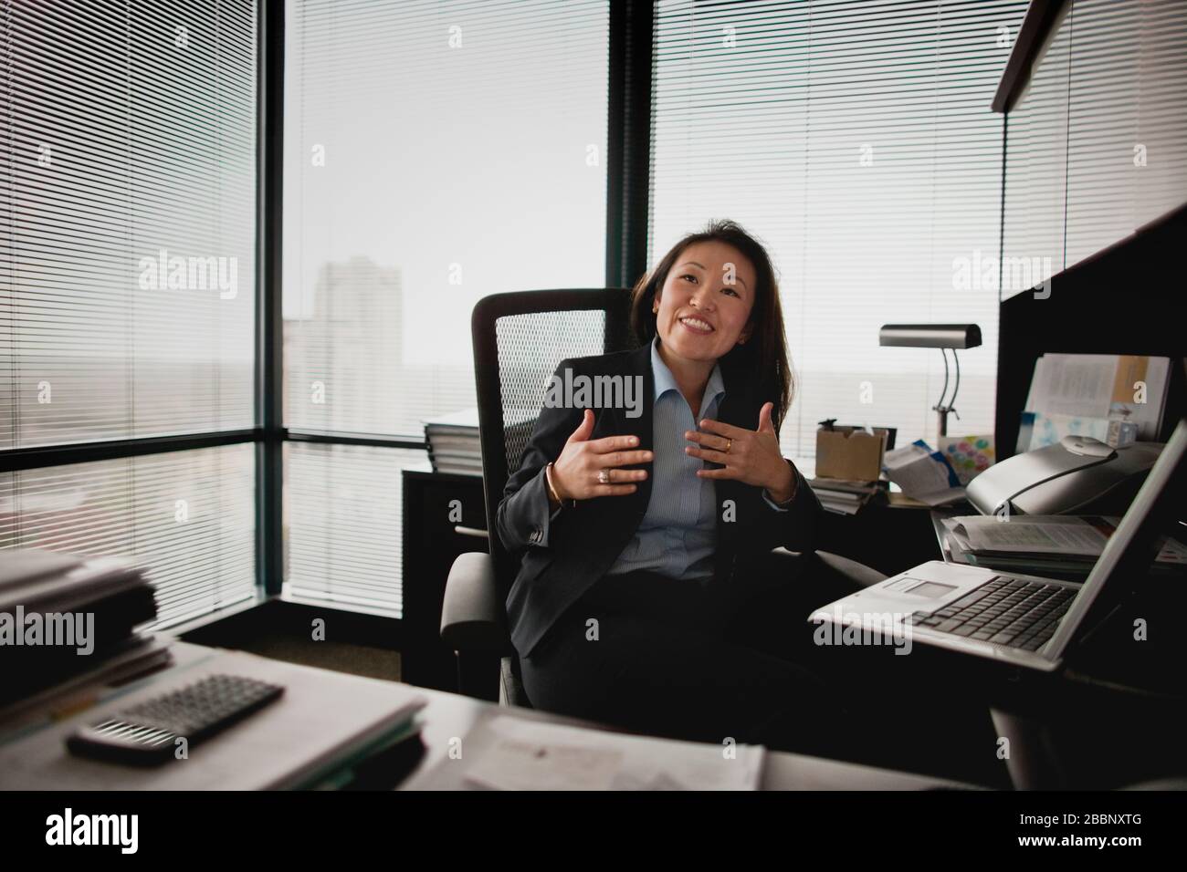 Woman talking and sitting at office desk Stock Photo - Alamy
