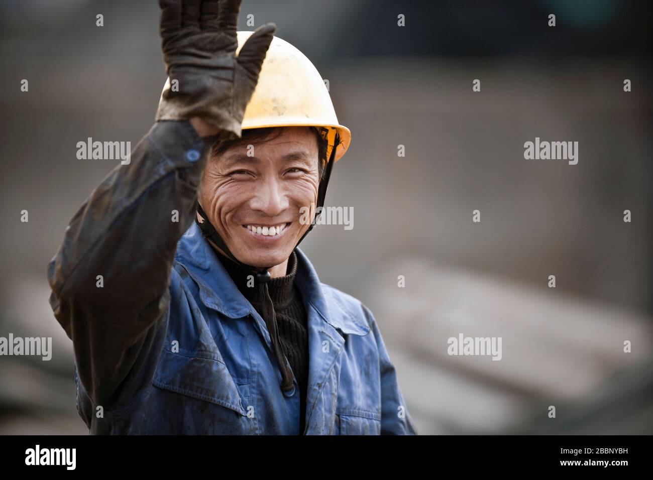 Construction worker on site, smiling and waving Stock Photo - Alamy