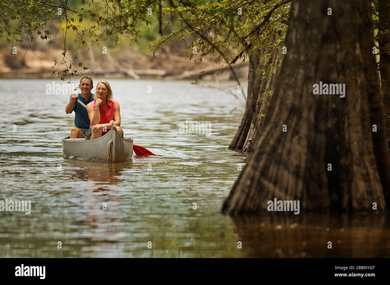 Smiling mature couple canoeing on a river in the woods Stock Photo - Alamy