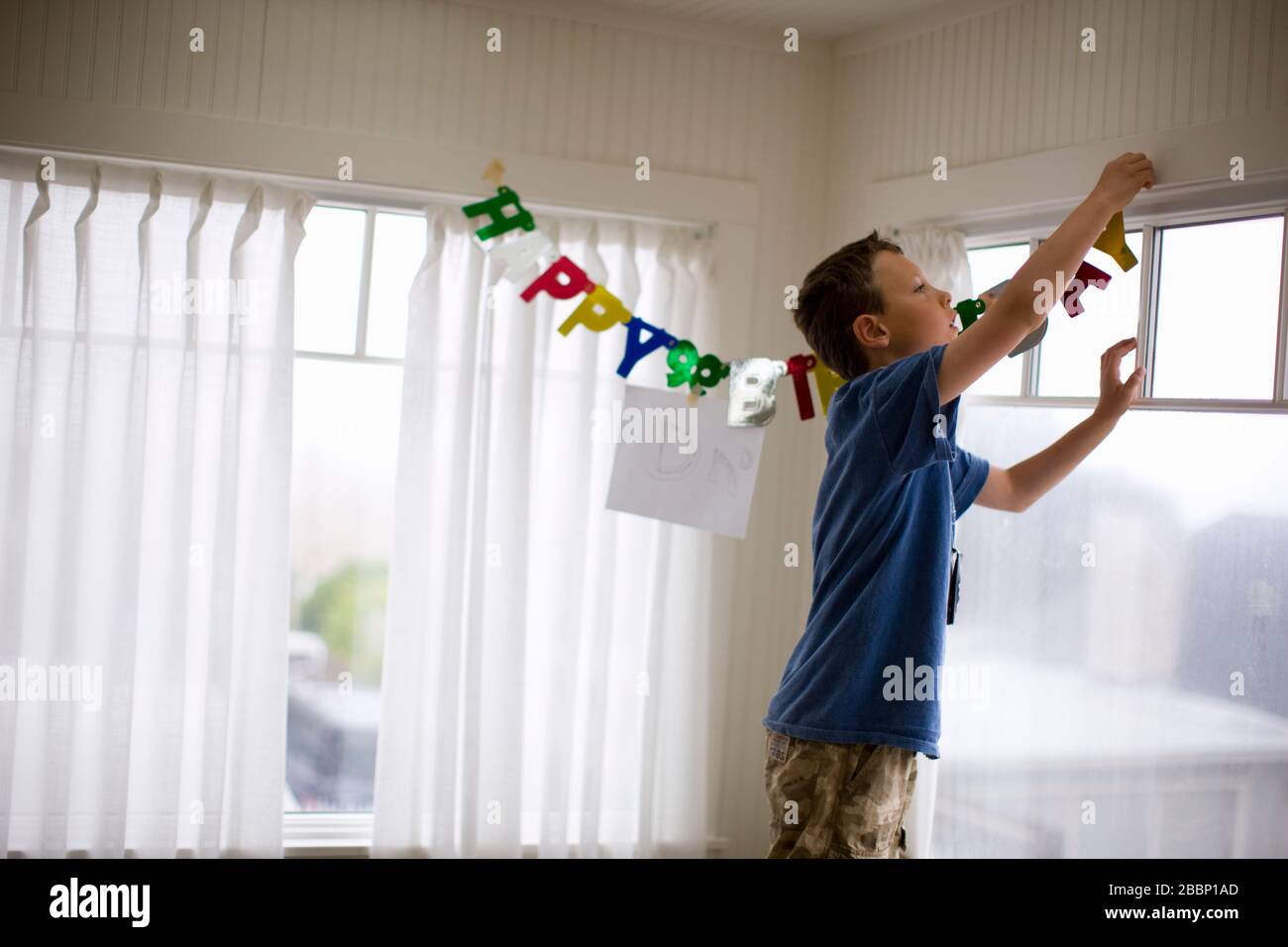 Boy hanging a 'Happy Birthday' sign Stock Photo - Alamy